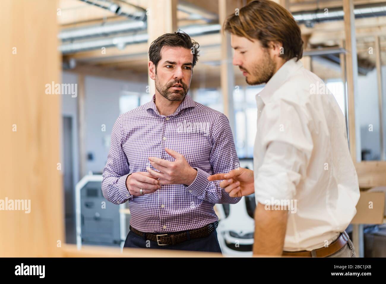 Two businessmen talking in wooden open-plan office Stock Photo - Alamy