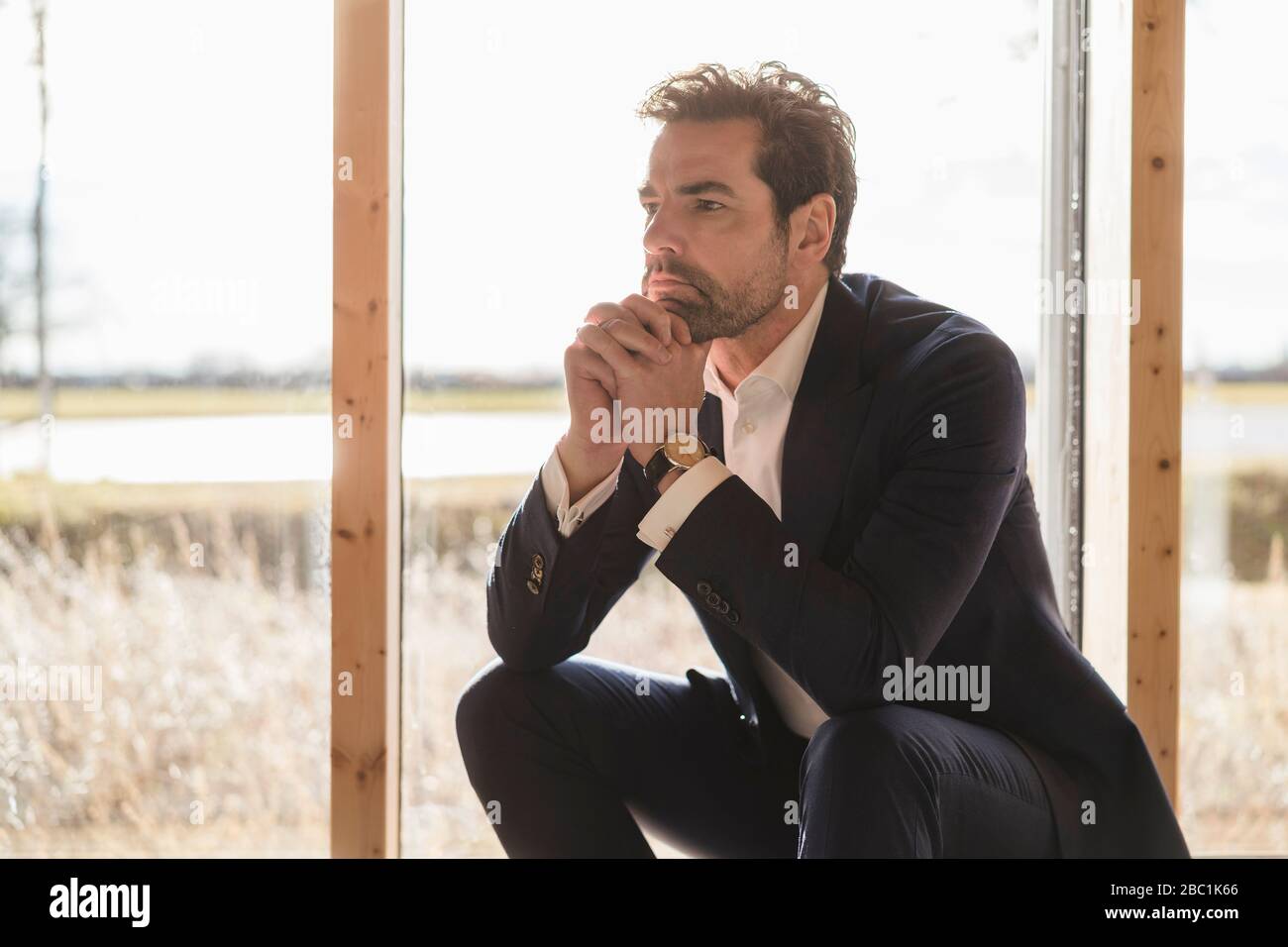 Serious businessman sitting at the window in office Stock Photo - Alamy
