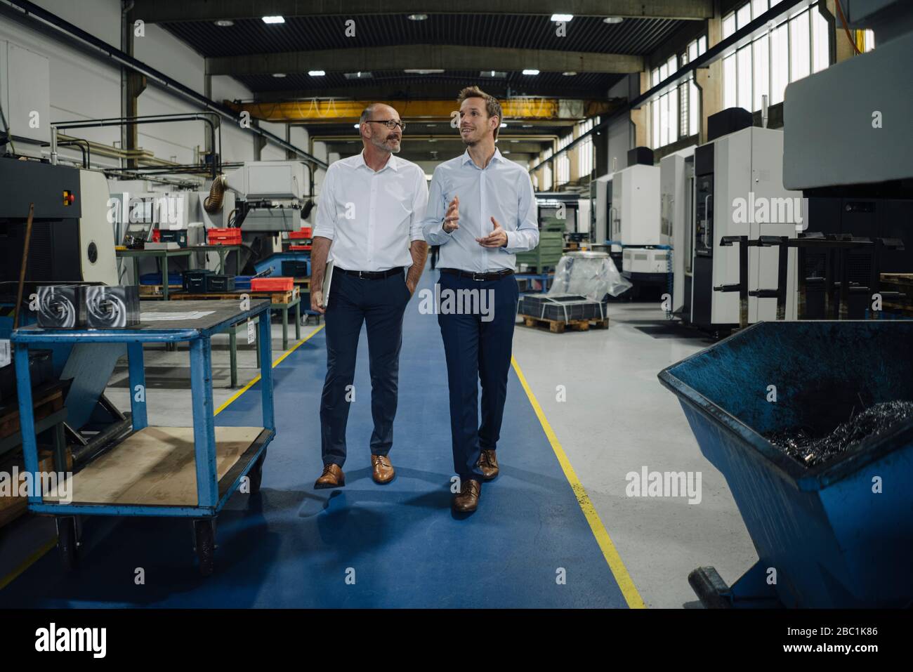 Two men walking and talking in a factory Stock Photo - Alamy