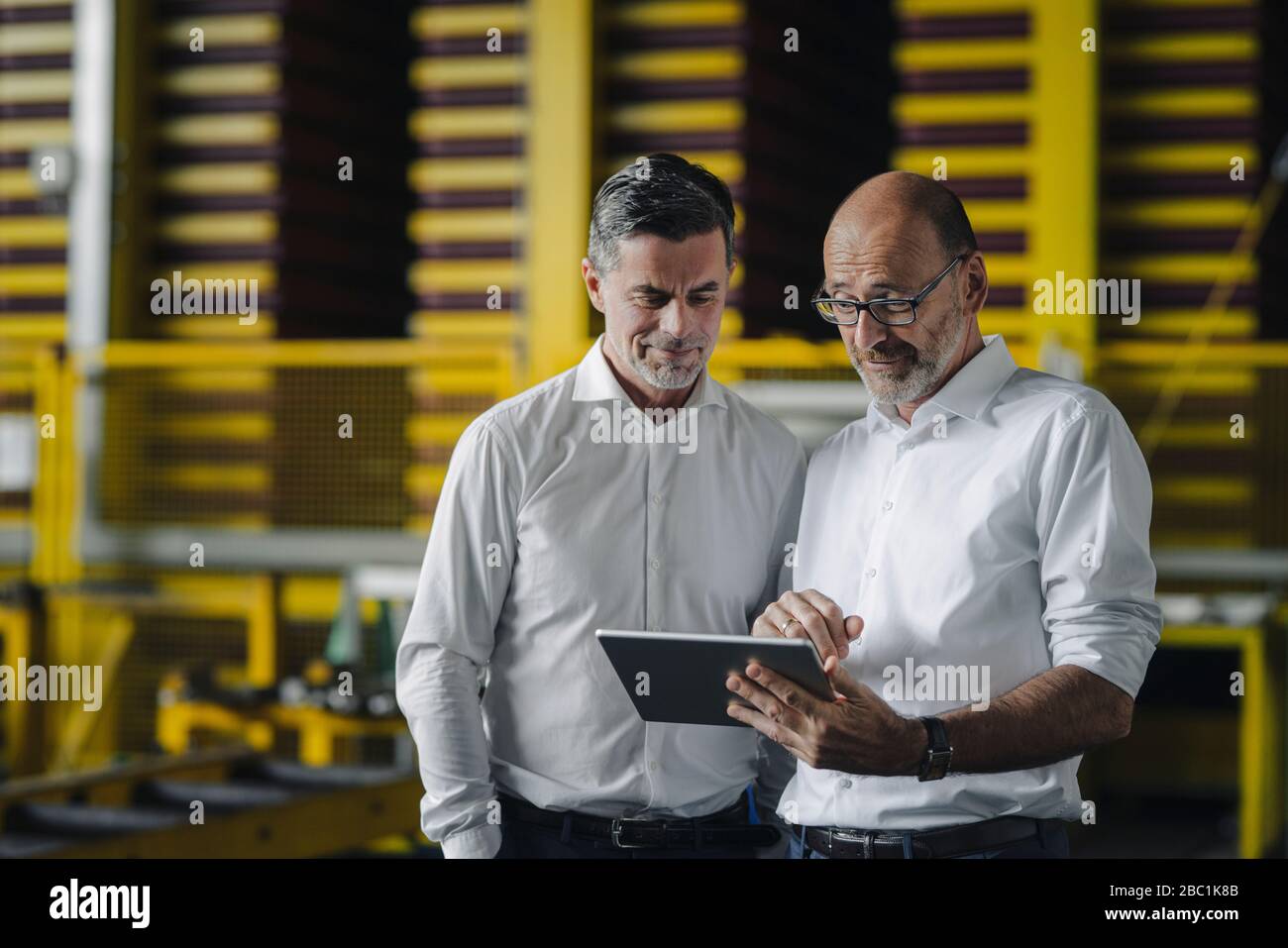 Two businessmen using tablet in a factory Stock Photo - Alamy