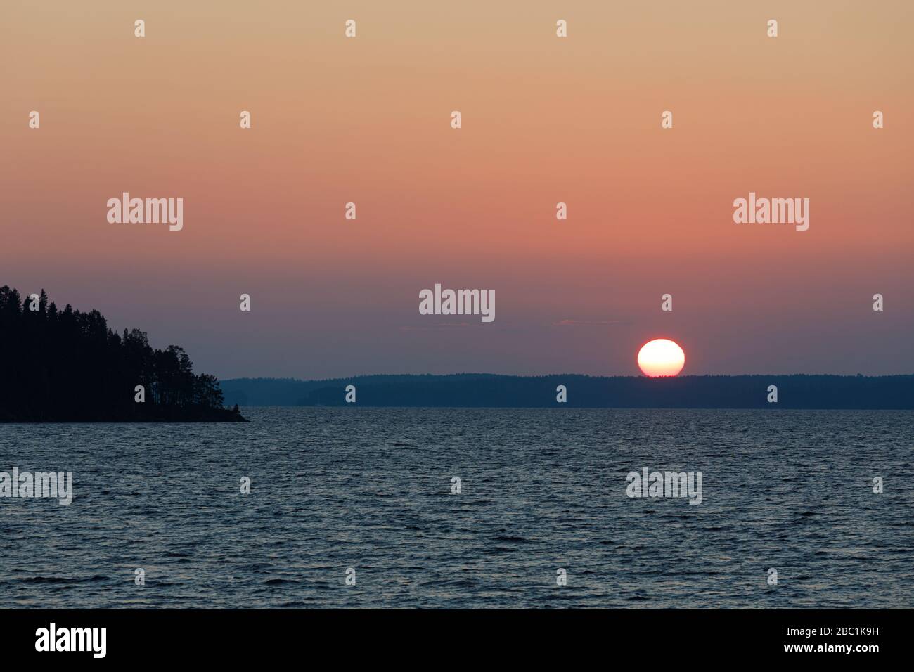 Big red sun rising over lake scene Stock Photo - Alamy