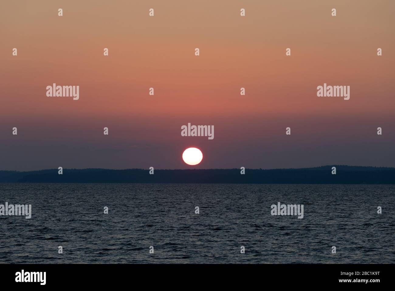Big red sun rising over lake scene Stock Photo - Alamy