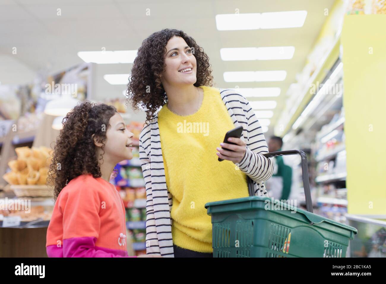 Mother and daughter with smart phone shopping in supermarket Stock ...