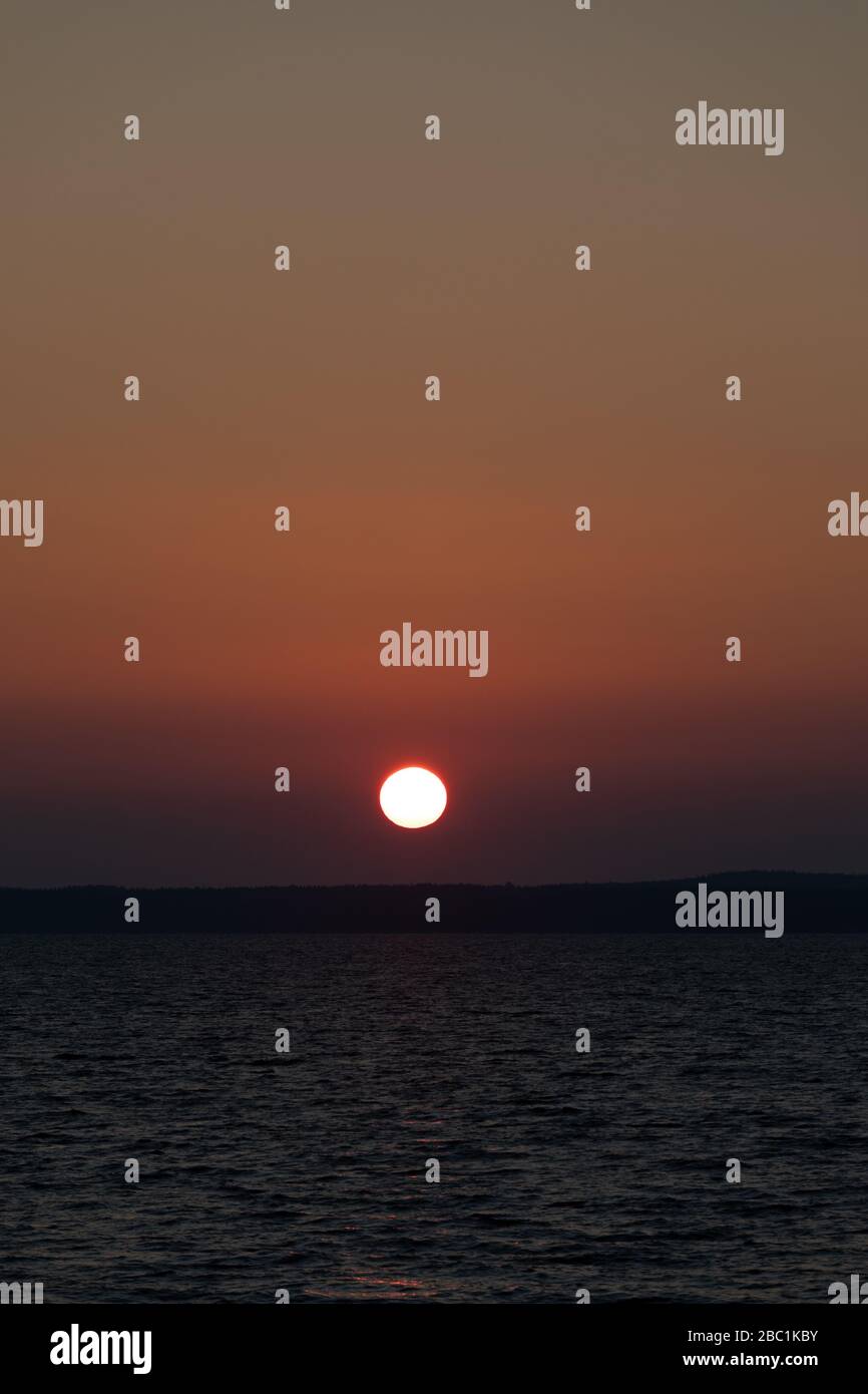 Big red sun rising over lake scene Stock Photo - Alamy