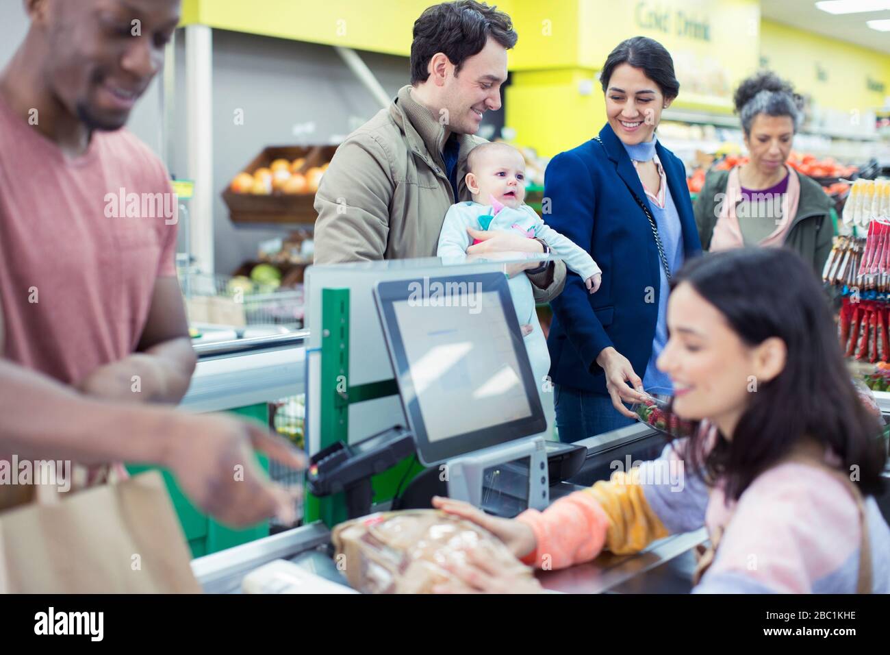 Cashier helping customers at supermarket checkout Stock Photo - Alamy