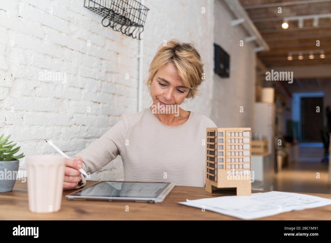 Mature woman working at desk in architectural office Stock Photo - Alamy
