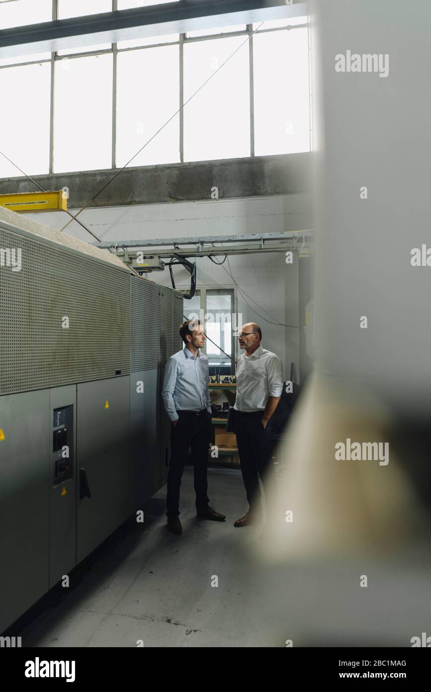 Two men standing in a factory Stock Photo - Alamy
