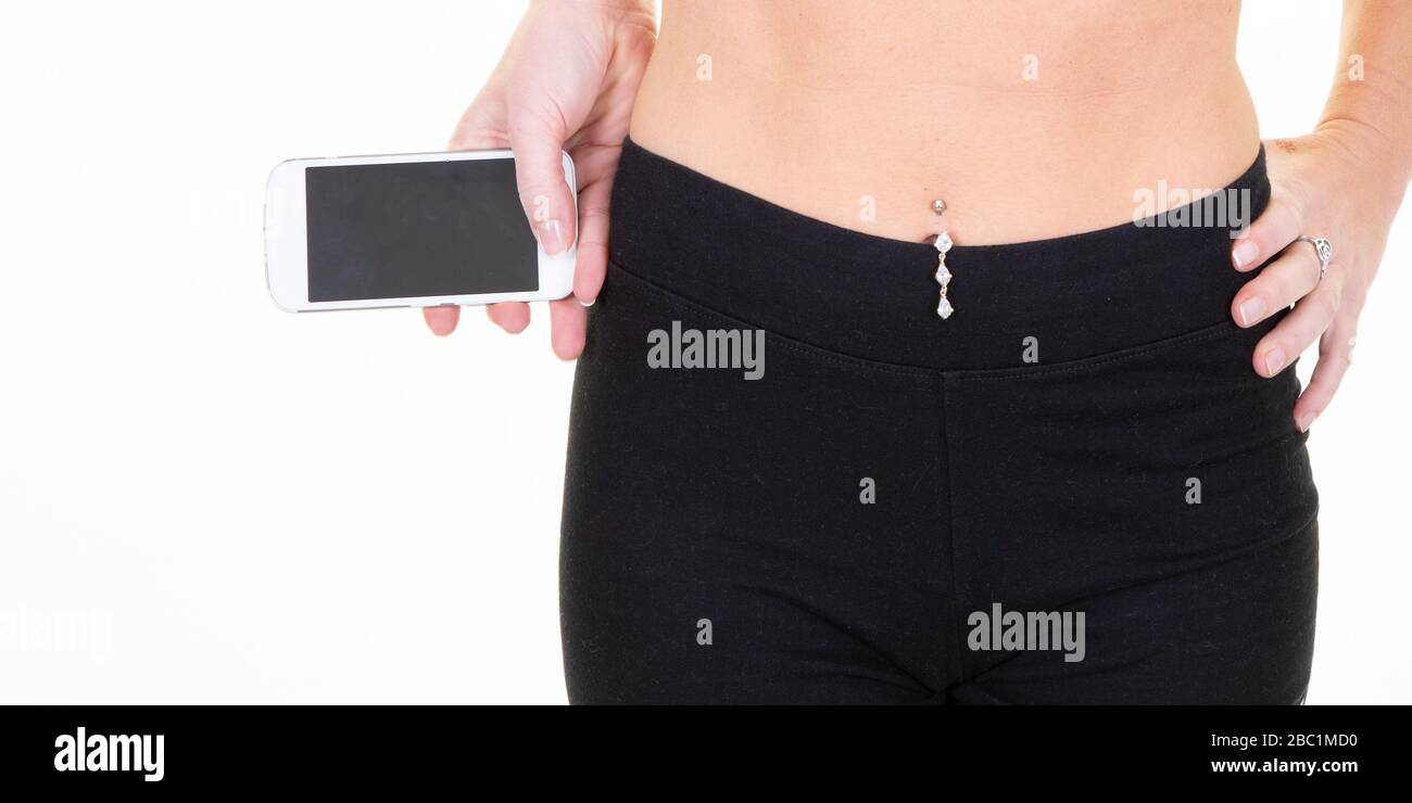 Fit young woman holding smartphone over belly abdomen isolated on white ...
