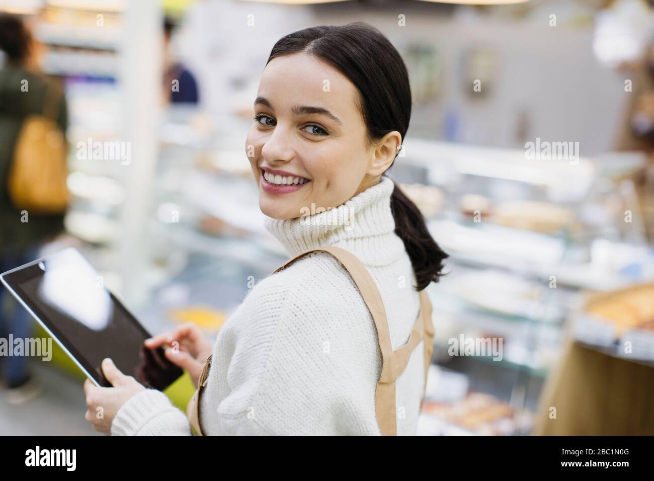 Portrait smiling, confident female grocer with digital tablet working ...