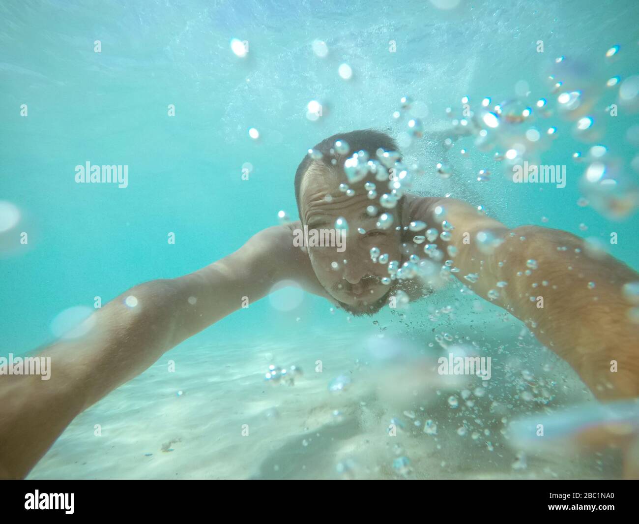 Under water photo of a man diving without equipment in turquoise sea ...
