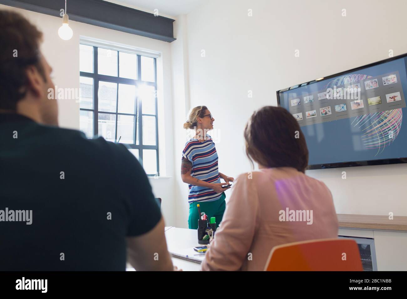 Female architect at television screen leading conference room meeting ...