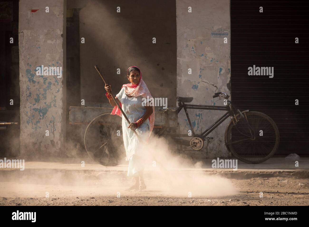 Woman sweeping a dusty street in Old Delhi, India Stock Photo - Alamy