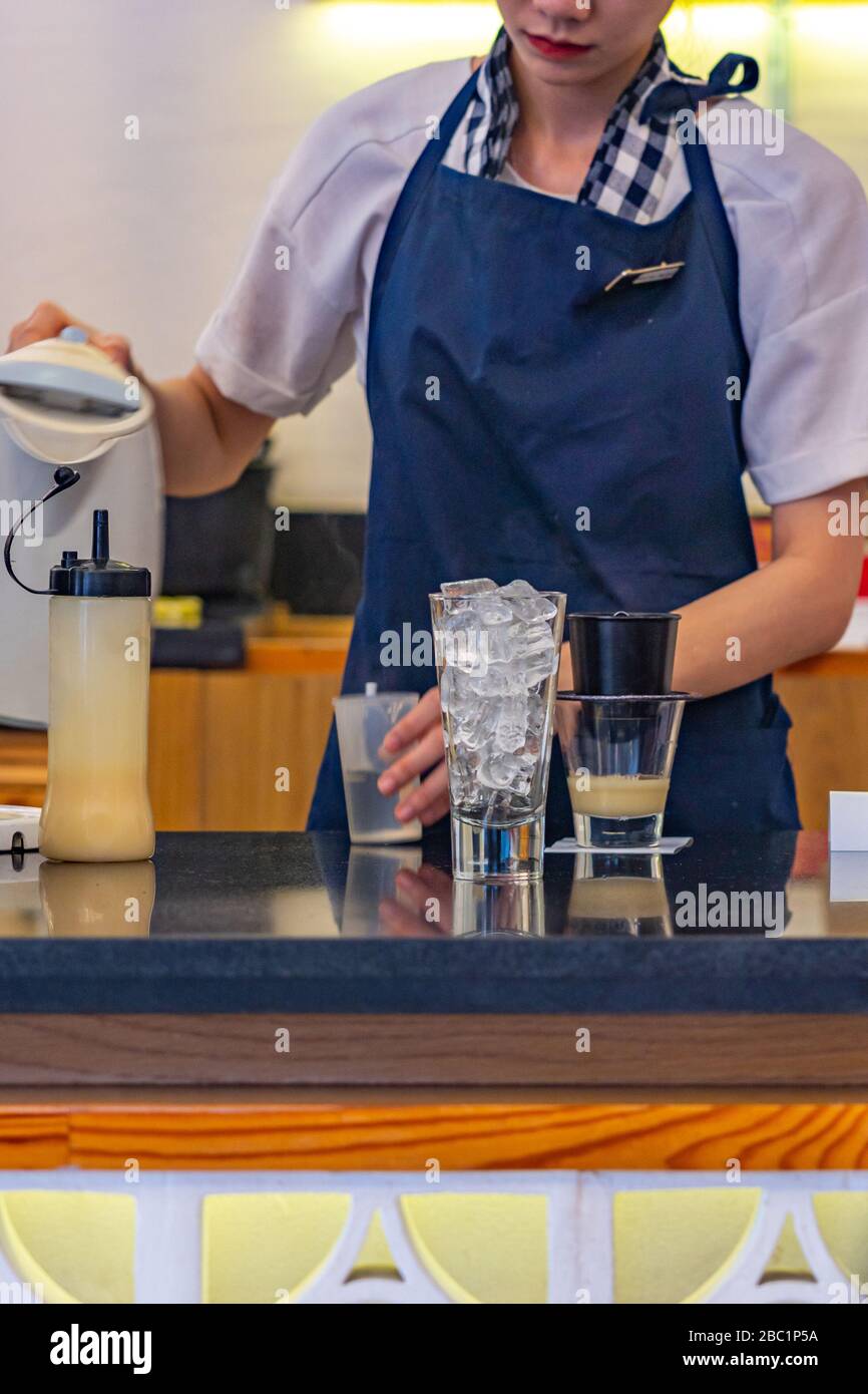 Barista brewing Vietnamese dripping coffee with condensed milk and ice ...