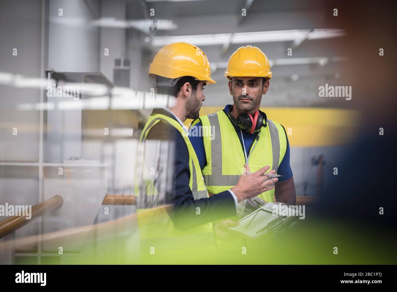 Male supervisor and worker with clipboard talking in factory Stock ...