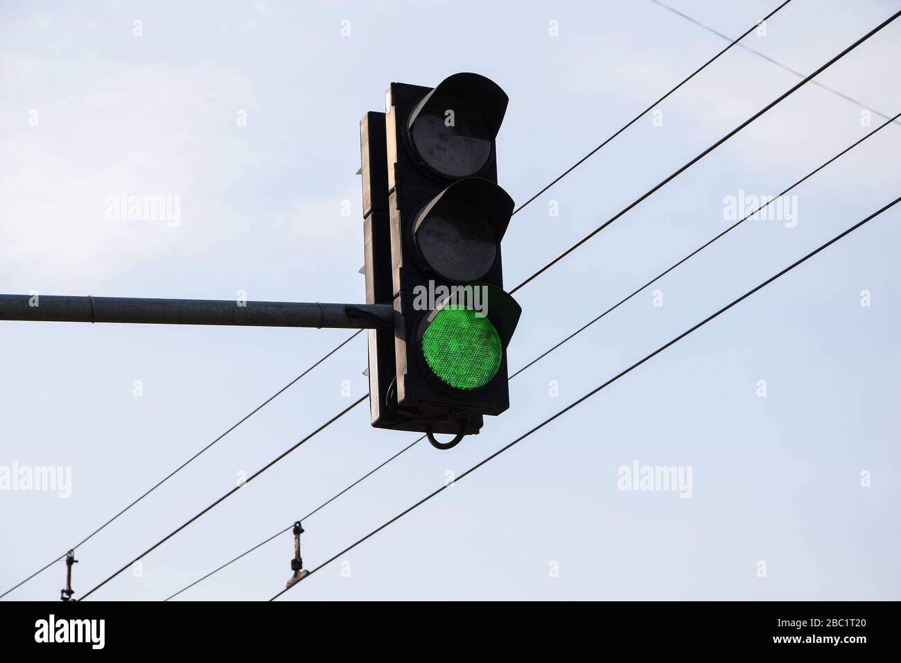 Green traffic light with green direction light against soft blue sky ...
