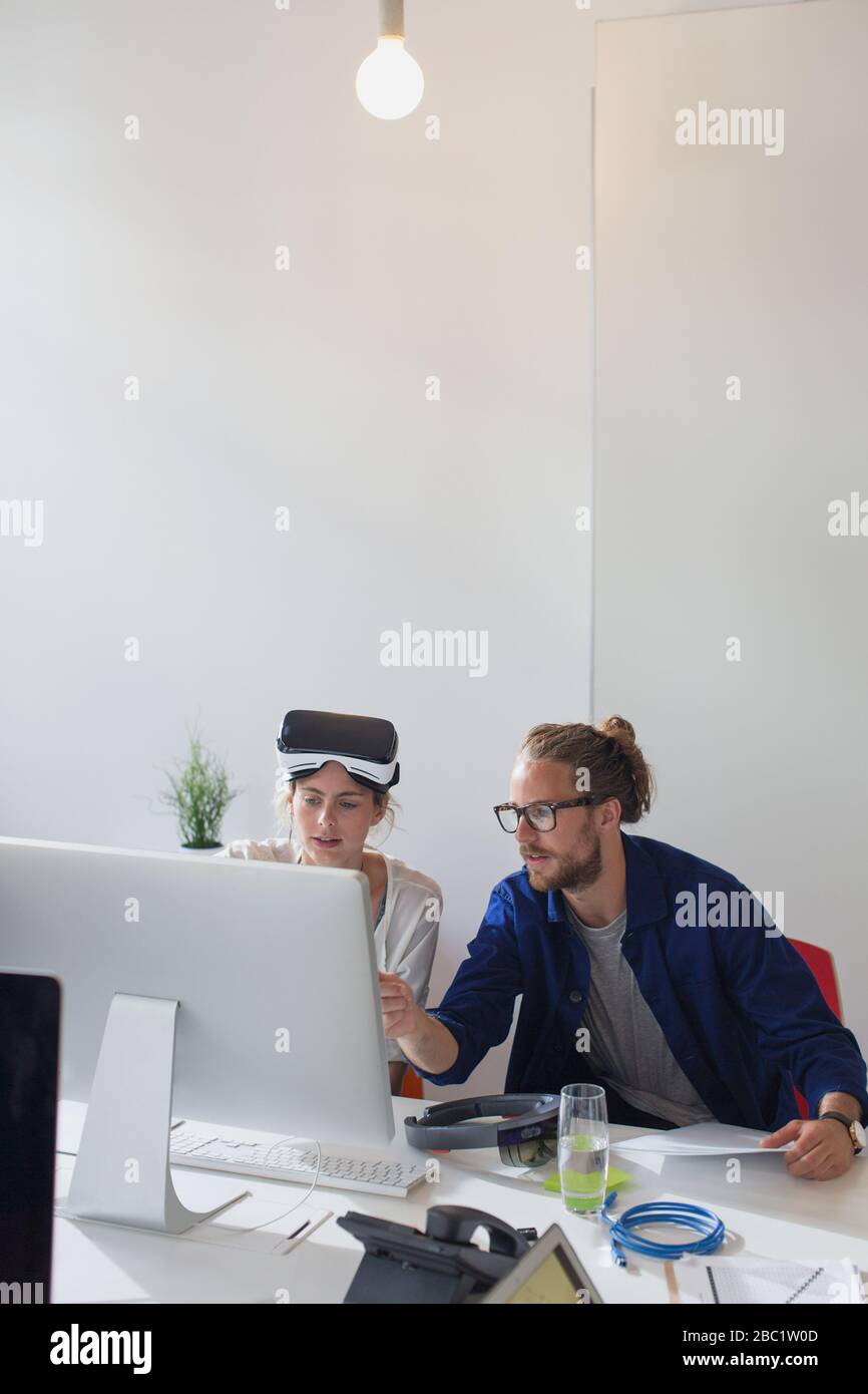 Computer programmers programming virtual reality simulator glasses at computer in office Stock ...