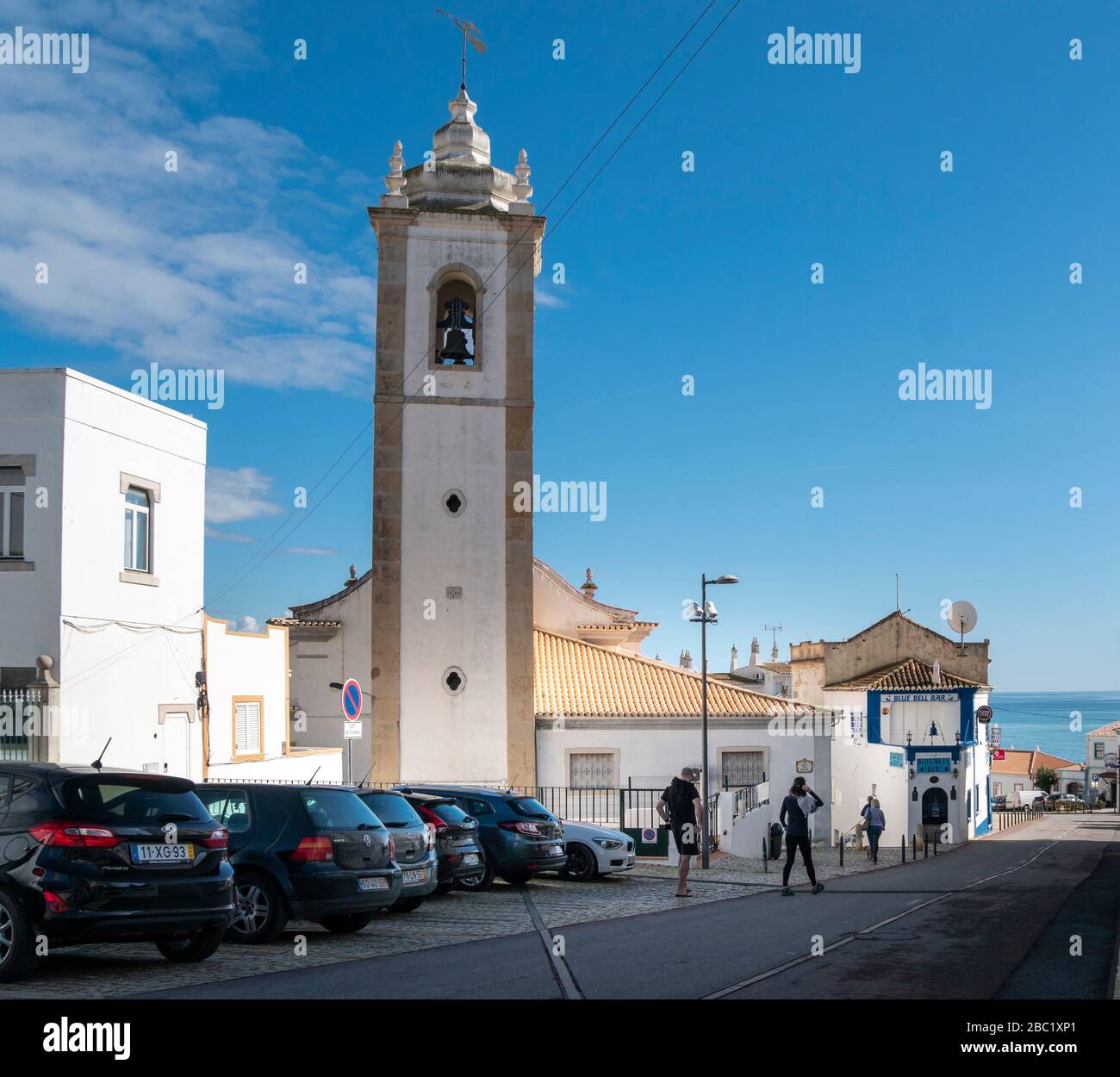Church bell tower and street view of the Atlantic ocean in Albufiera ...