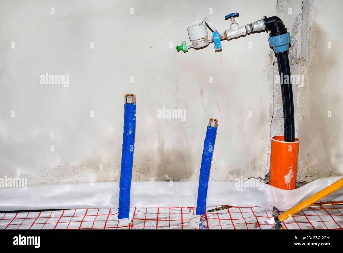 Two blue plastic pipes with cold water coming out of the floor and ...