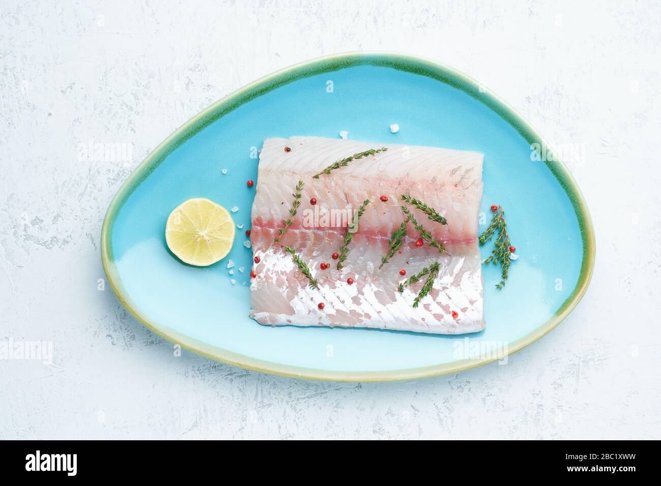 Fillet of raw white walleye fish on a blue plate on a white background ...
