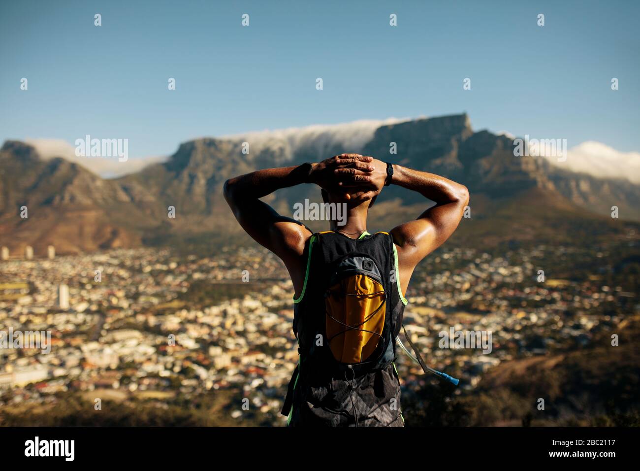Rear view of athletic man standing with his hands behind head and ...