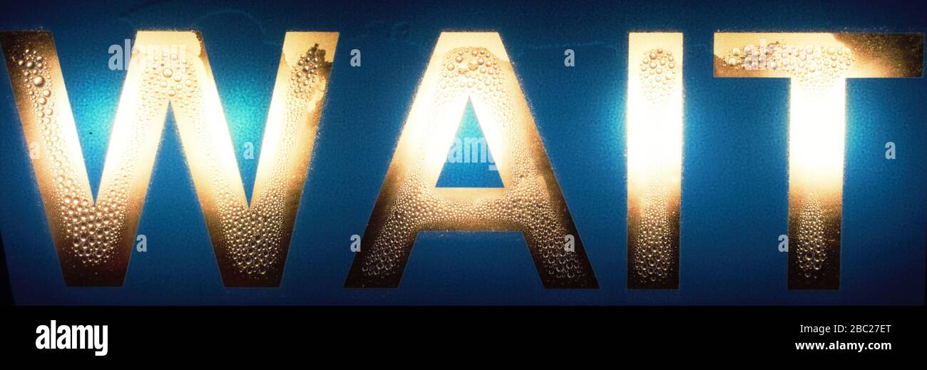 Illuminated wait sign on blue background Stock Photo - Alamy