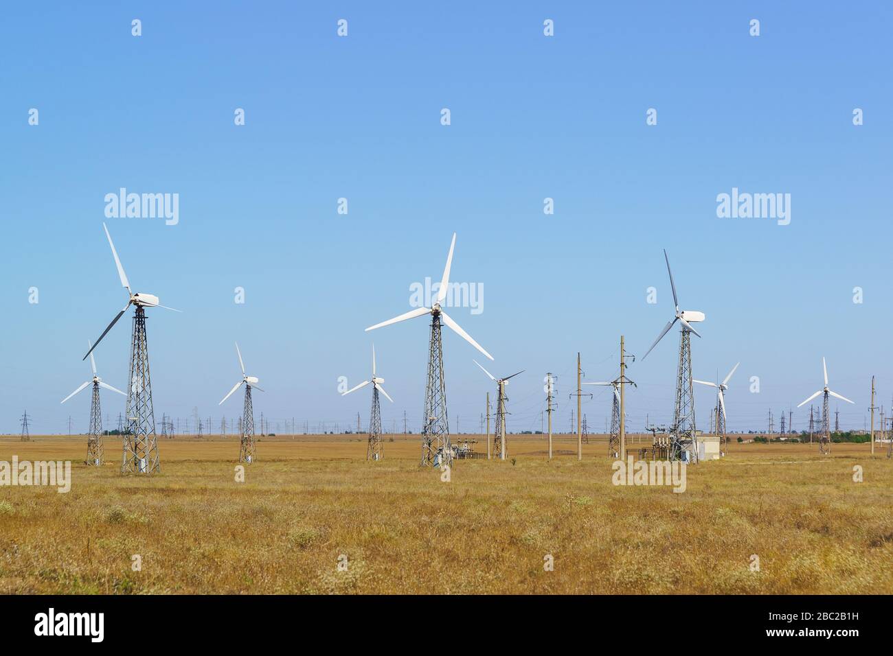 Lots of spinning wind turbines against a clear blue sky. Ground for ...
