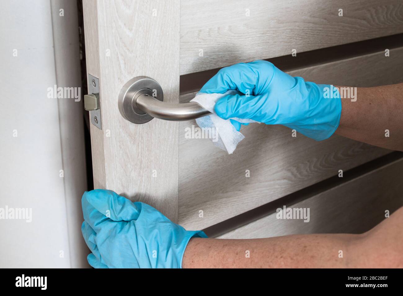 Coronavirus, covid 19 protection. Woman disinfects and cleans door ...