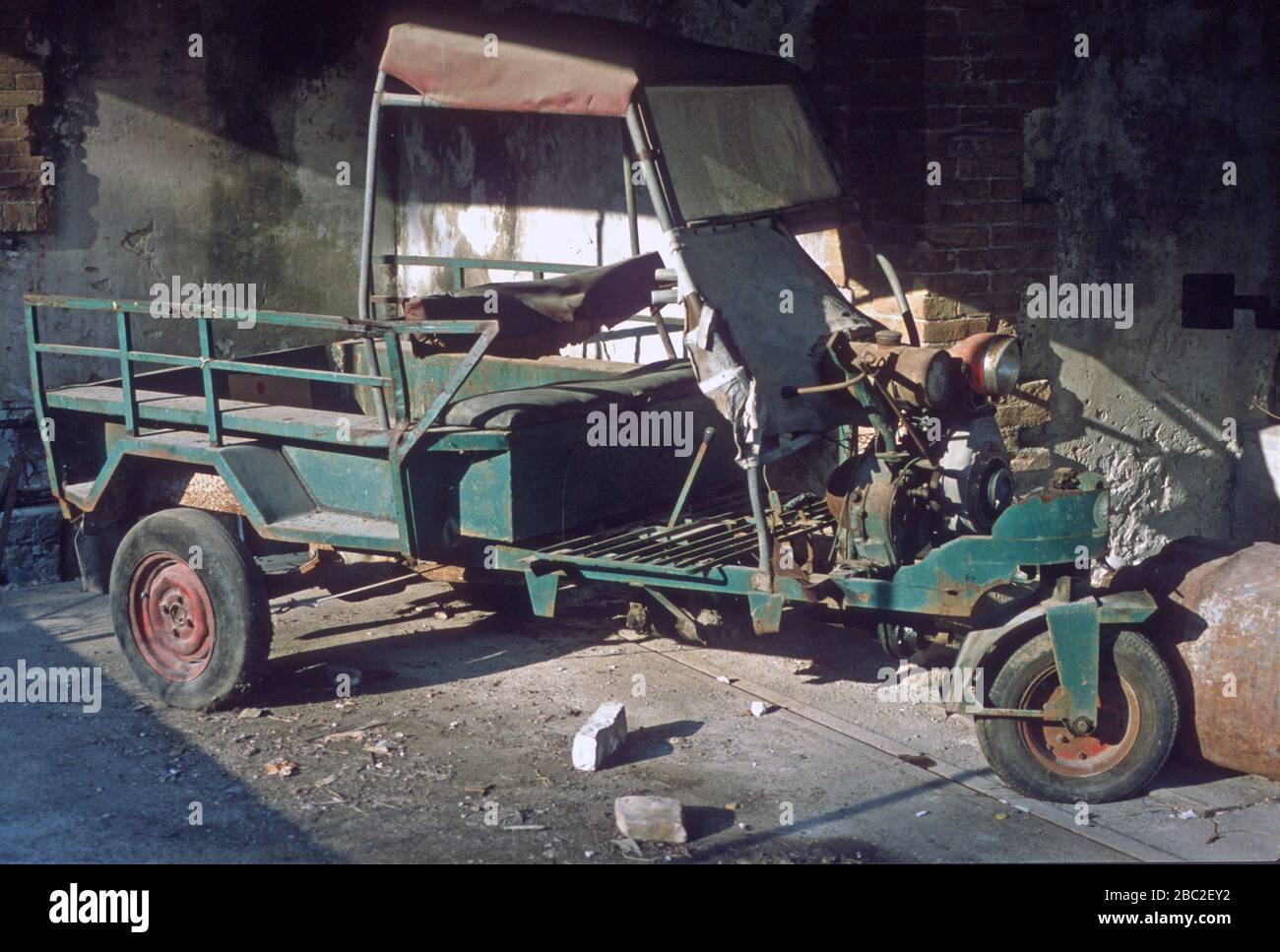 Old, green, rusting, three-wheel, farm vehicle in a shed on Paxos ...