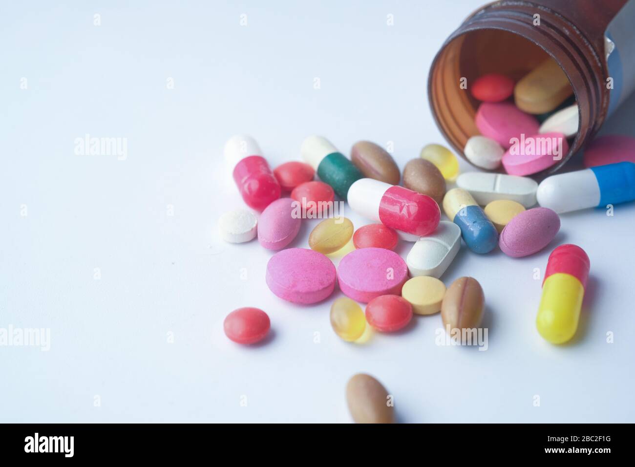 color pills spilling from container on isolated on white Stock Photo ...