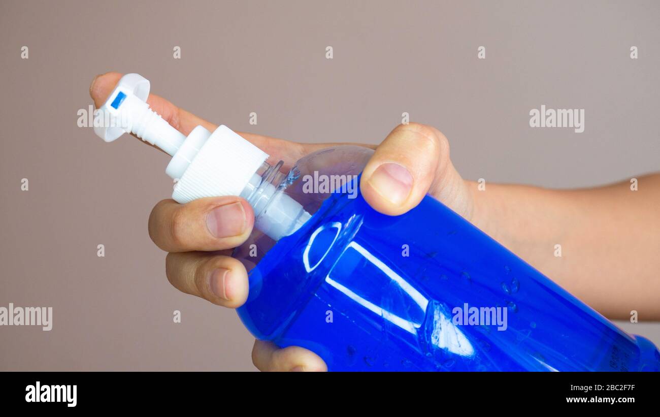 Woman's hand holding bottle of blue alcohol gel. Health care concept ...