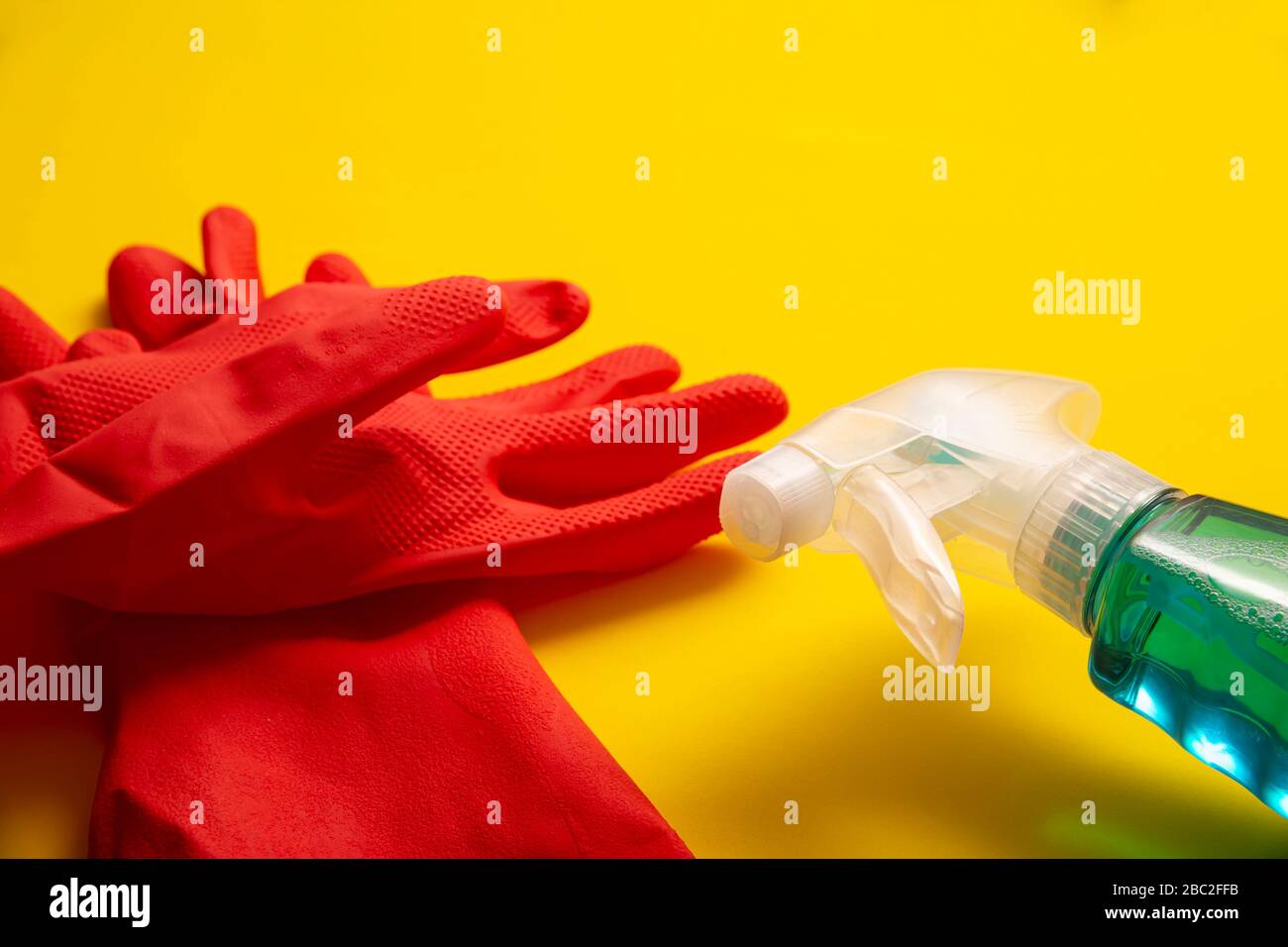 red rubber gloves and liquid detergent in sparay bottle on yellow ...