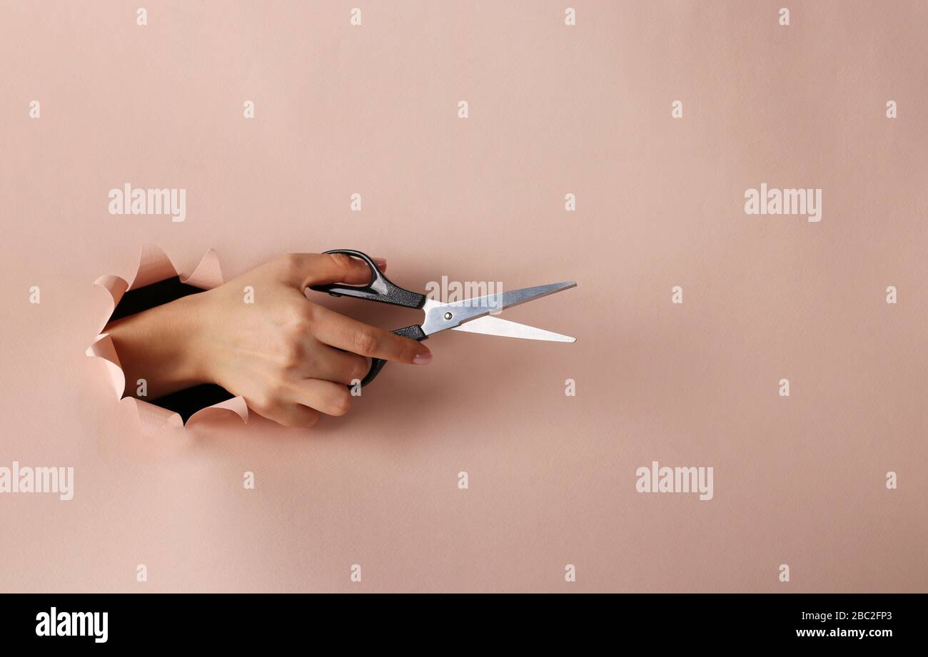 Female hand holding scissors through round hole in pink paper, Copy ...