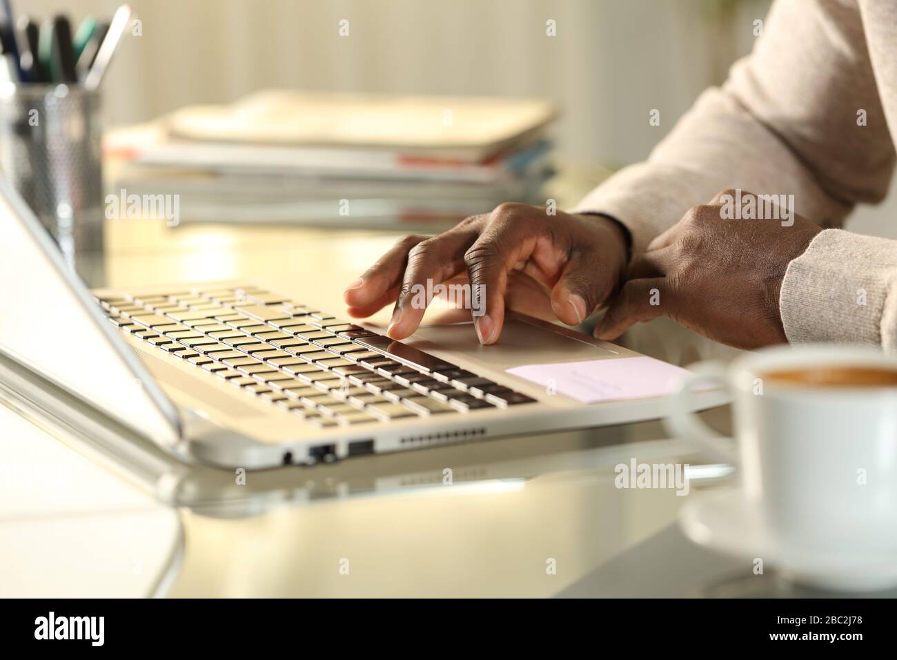 Close up of black man hands using touchpad on laptop on a desk at home ...