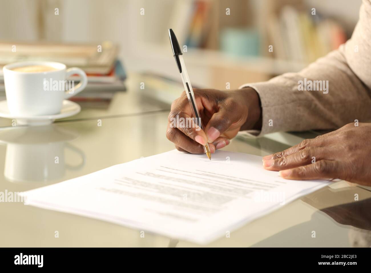 Close up of a black man hands singing contract on a desk at home Stock ...