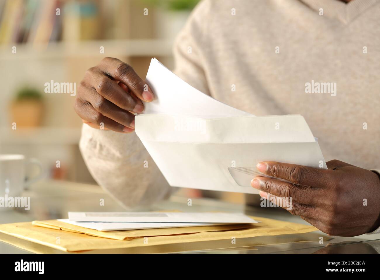 Close up of black man hands putting a letter inside an envelope on a ...