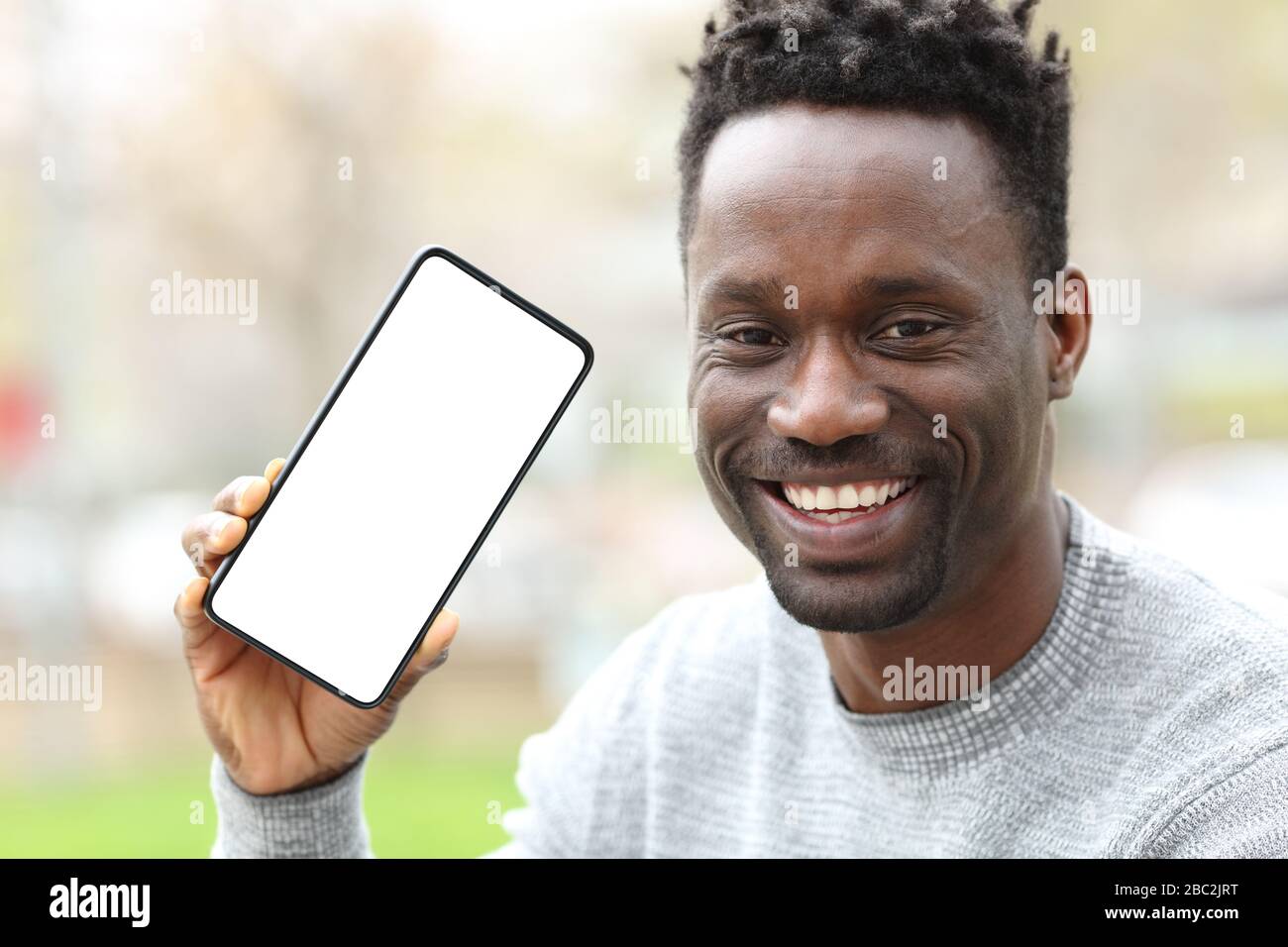 Front view portrait of a happy black man showing smart phone with blank ...