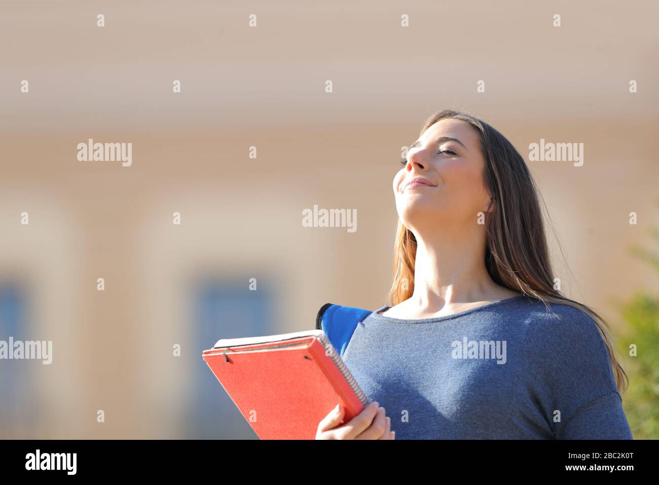 Happy student breathing fresh air standing outdoors in a university ...