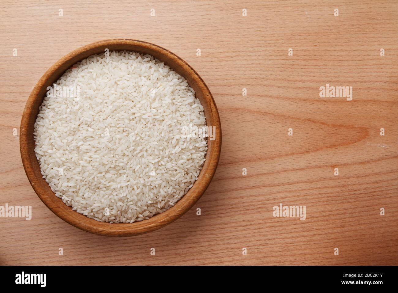 Raw rice in wooden bowl Stock Photo - Alamy