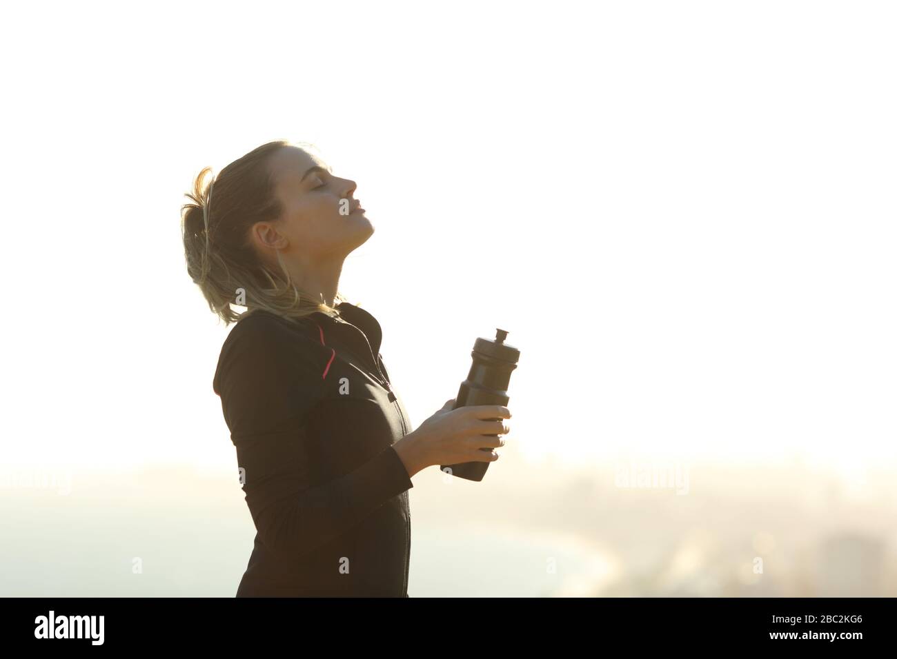 Side view portrait of a relaxed runner girl breathing fresh air holding ...