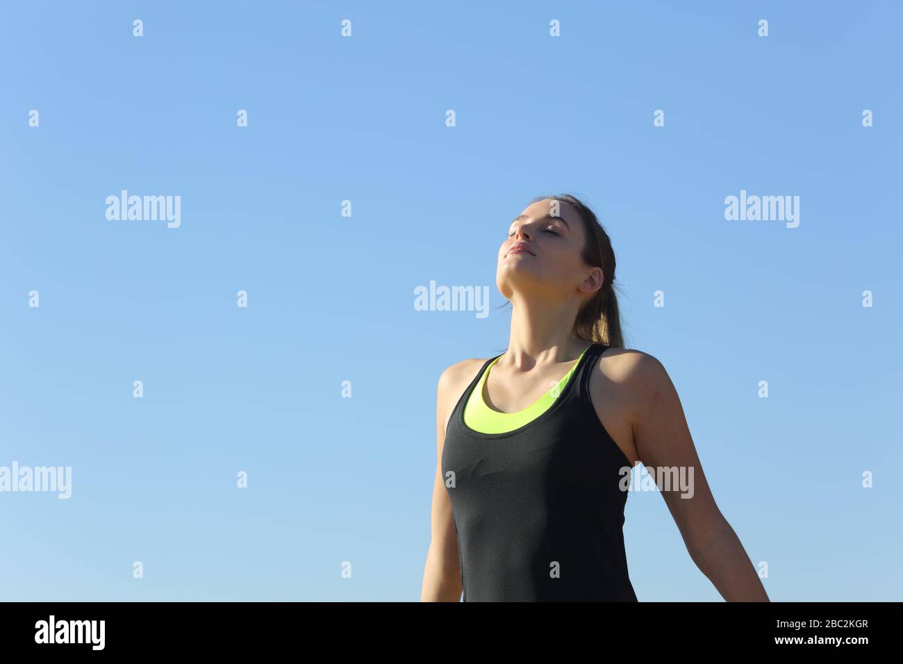 Relaxed runner woman breathing fresh air outdoors with the blue sky in ...