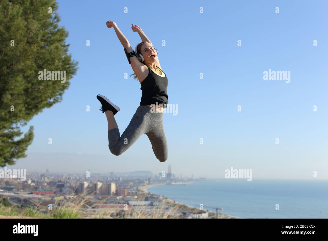 Excited runner wearing headphones jumping celebrating success Stock ...