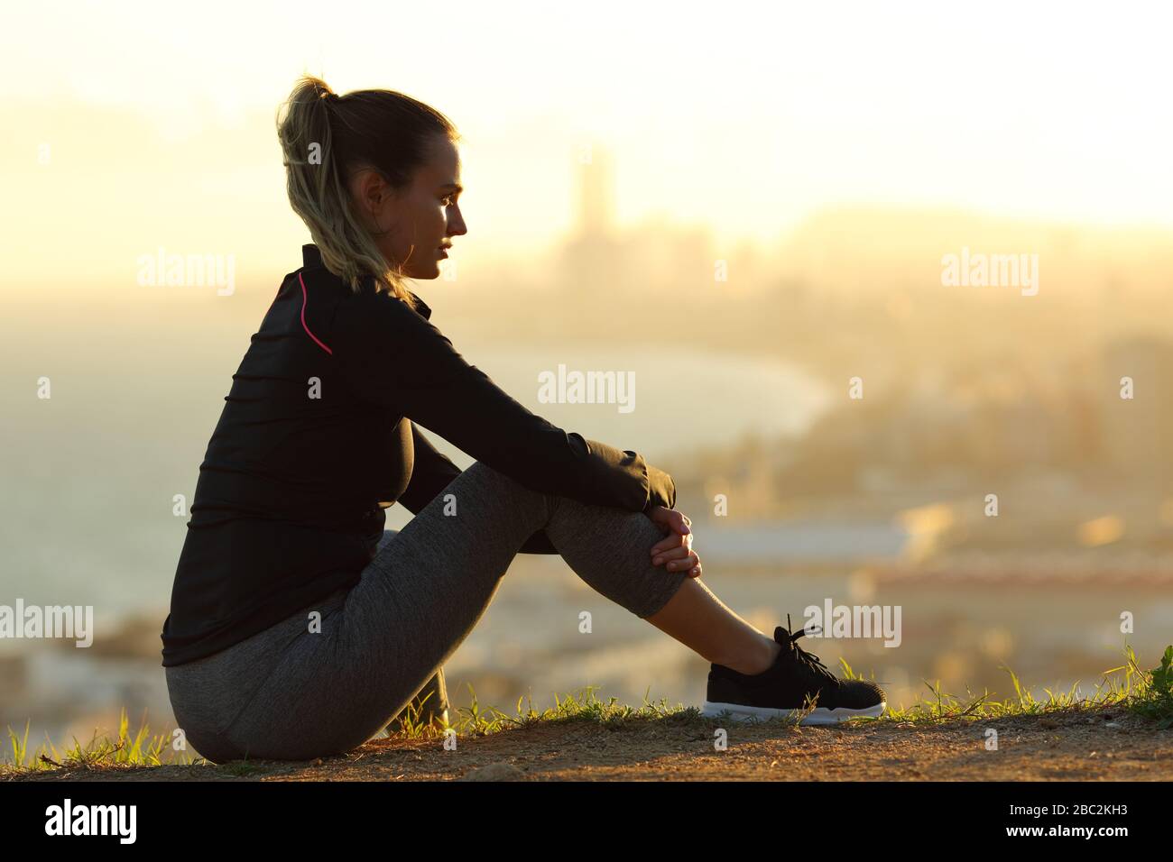 Profile of a serious runner sitting in city outskirts contemplating ...