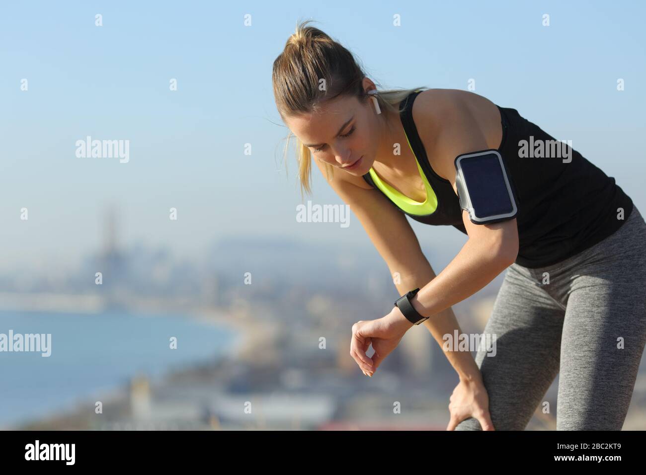 Tired runner checking smartwatch controlling pulsations after exercise ...