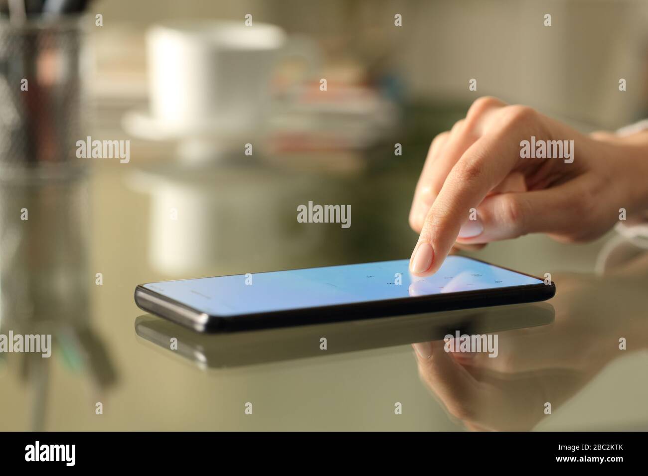 Close up of woman hands entering numbers on a lightened smart phone ...