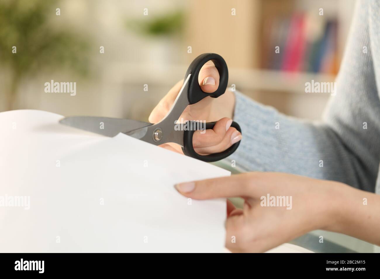 Close up of woman hands cutting paper sheet with scissors on a desk at ...