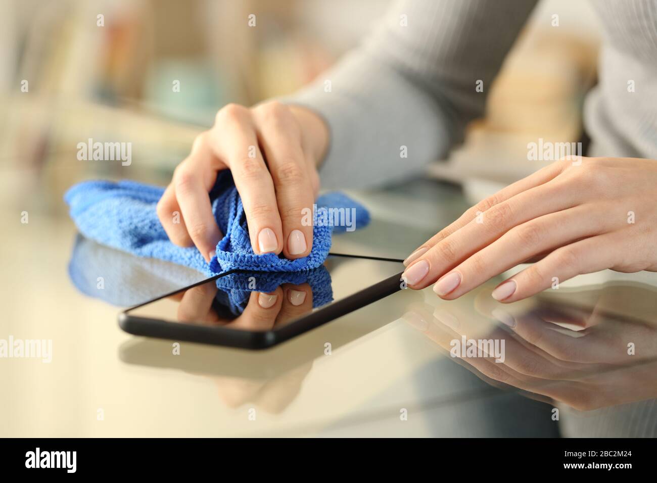 Close up of woman hands cleaning smart phone screen with a cloth on a ...