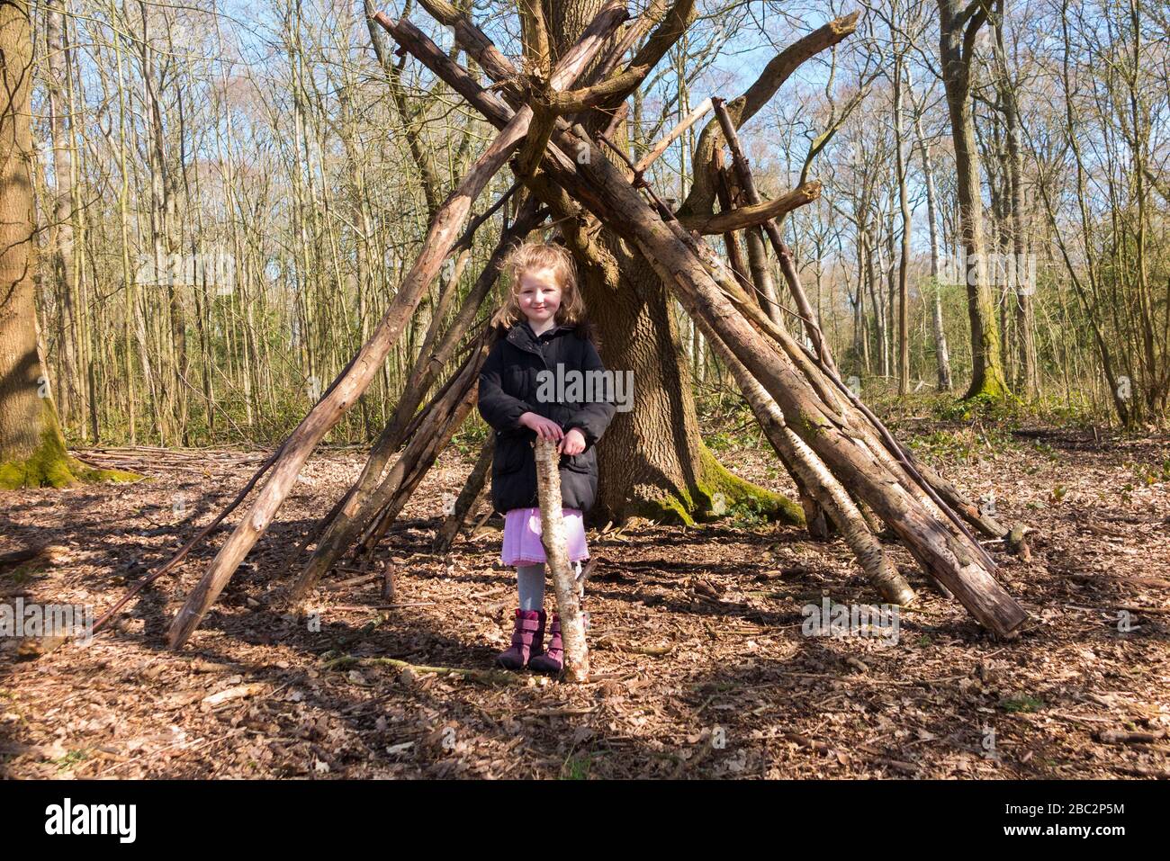 Kid / kids / Young girl and a wigwam stack of trees branches leant up ...