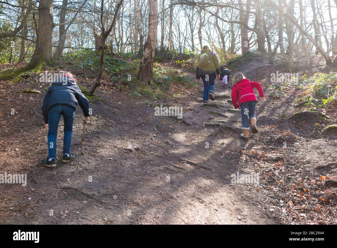 Mother & 3 children three kids daughters walking / walk up a steep hill ...