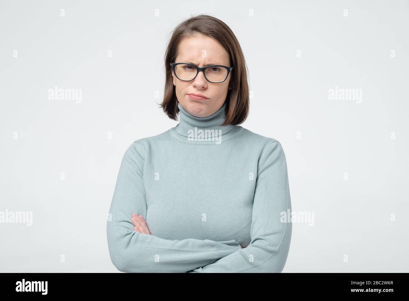 Serious young woman with disapproving expression on her face suspecting ...