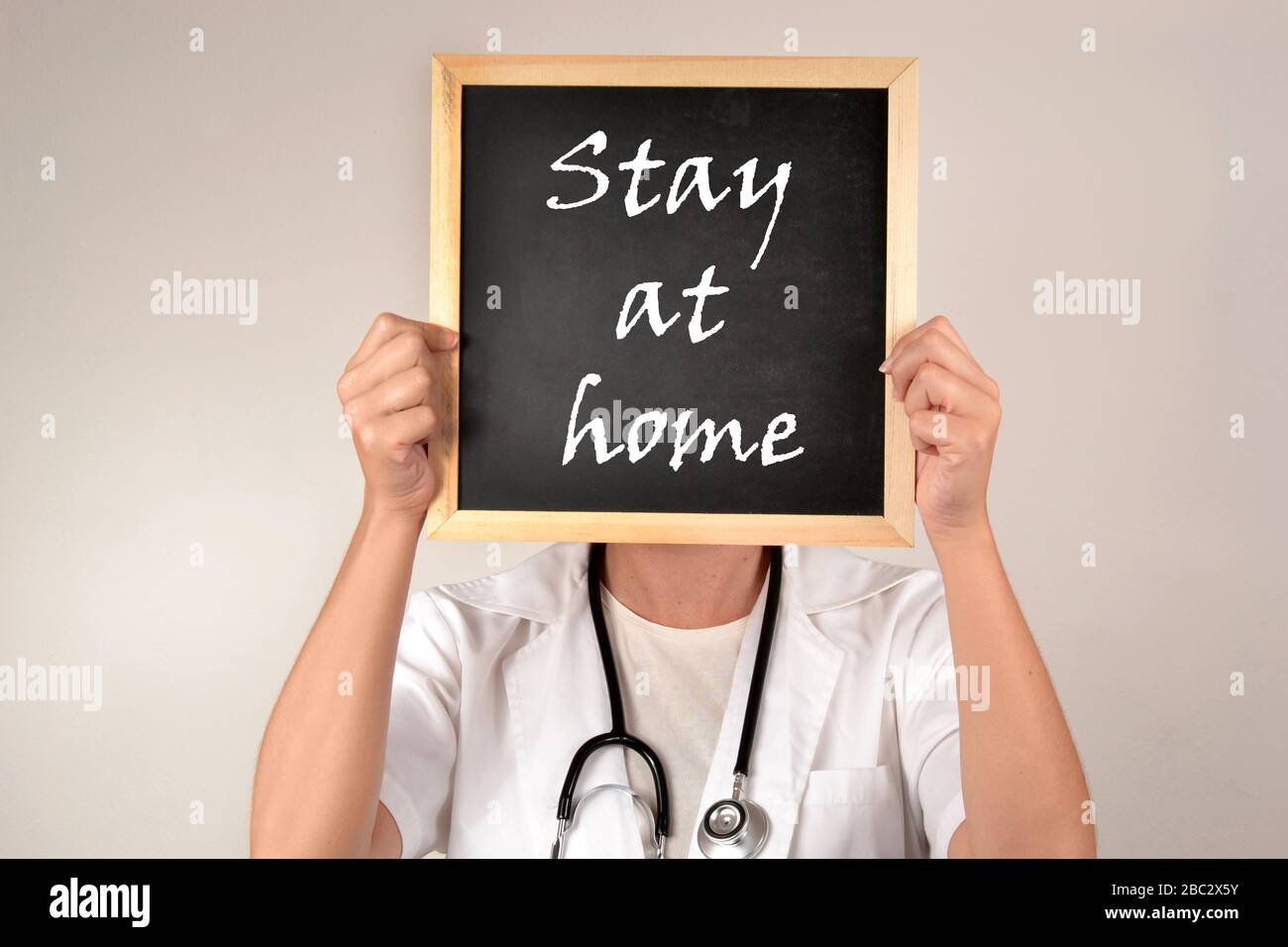 Doctor with a blackboard and message stay at home Stock Photo - Alamy
